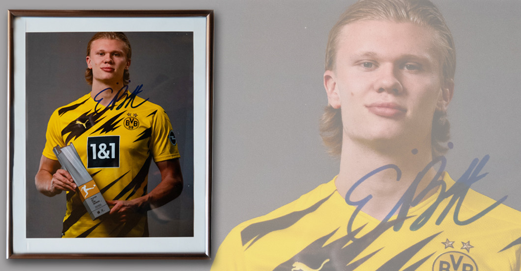 Erling Haaland signiert eine Fotografie aus seiner BVB-Zeit