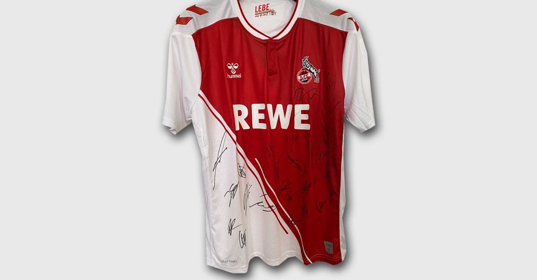 Die Mannschaft des 1. FC Köln signiert ein aktuelles Trikot
